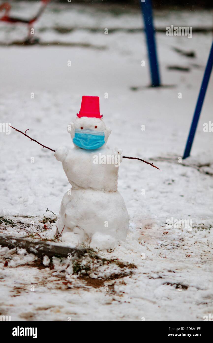 Snowman wearing protection mask standing outdoors on playground on a ...