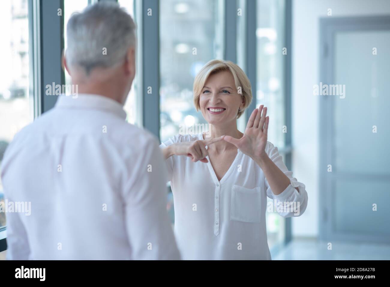 Blonde female having conversation with gray-haired male using sign ...