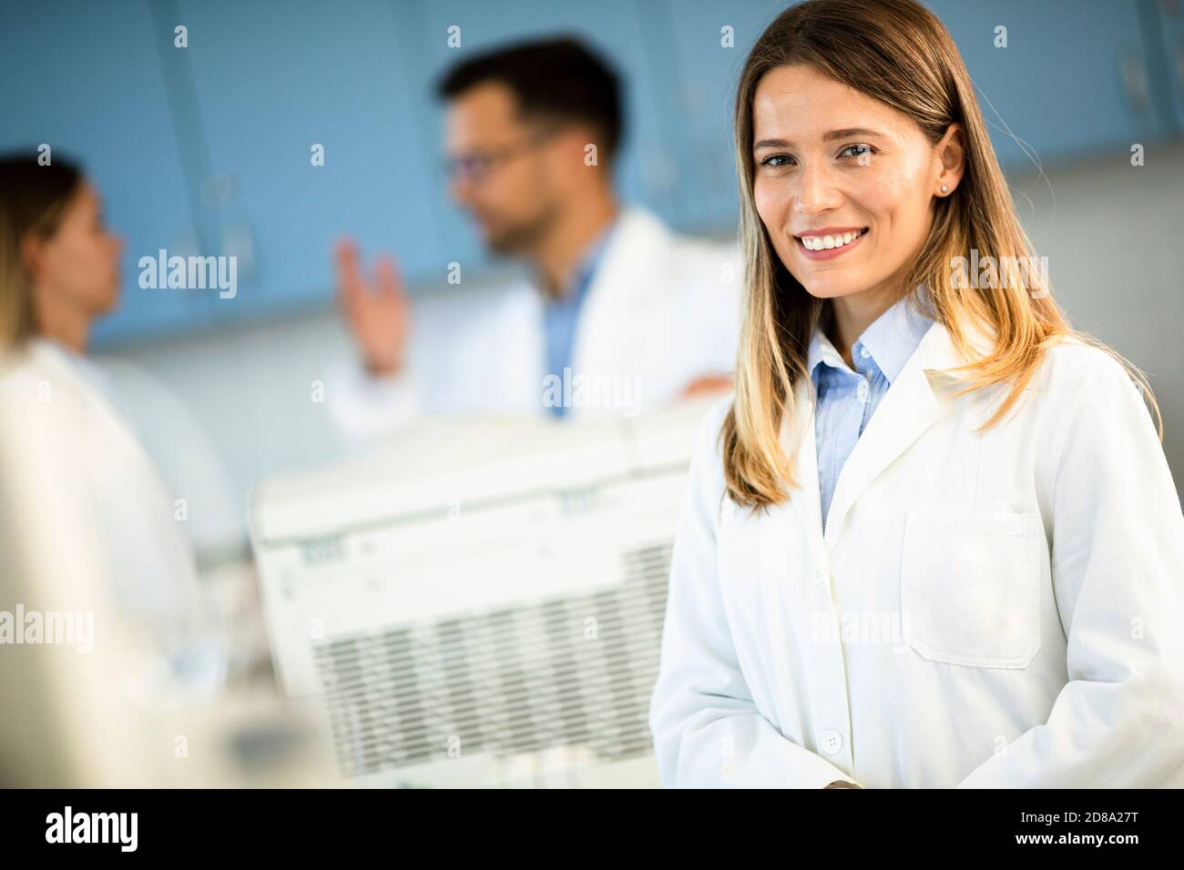 Young female scientist in white lab coat standing in the biomedical lab ...