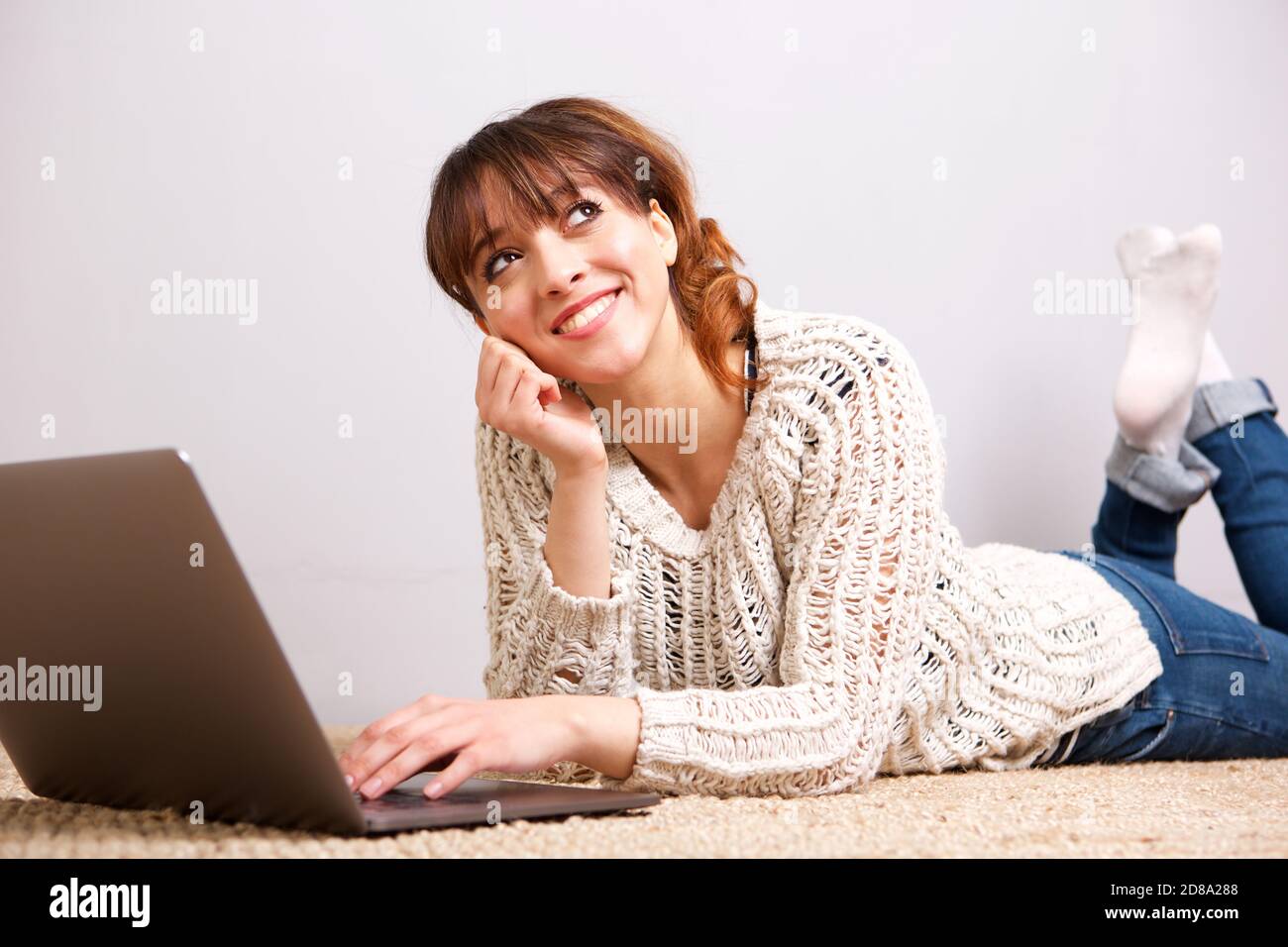 Portrait of happy young woman lying on floor with laptop computer Stock ...