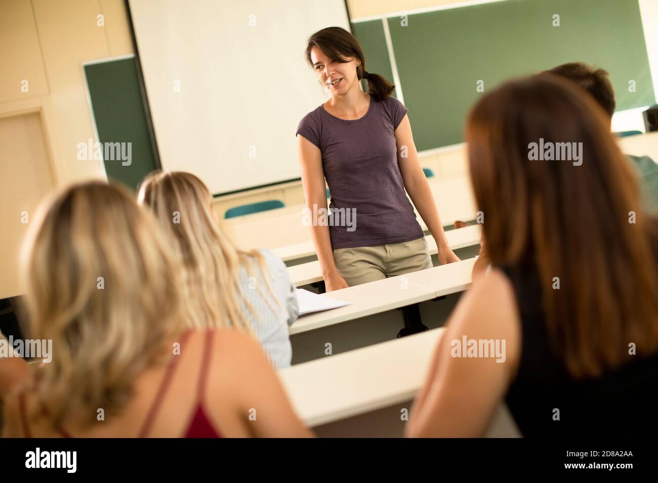 Group of university students in the classroom with young female ...