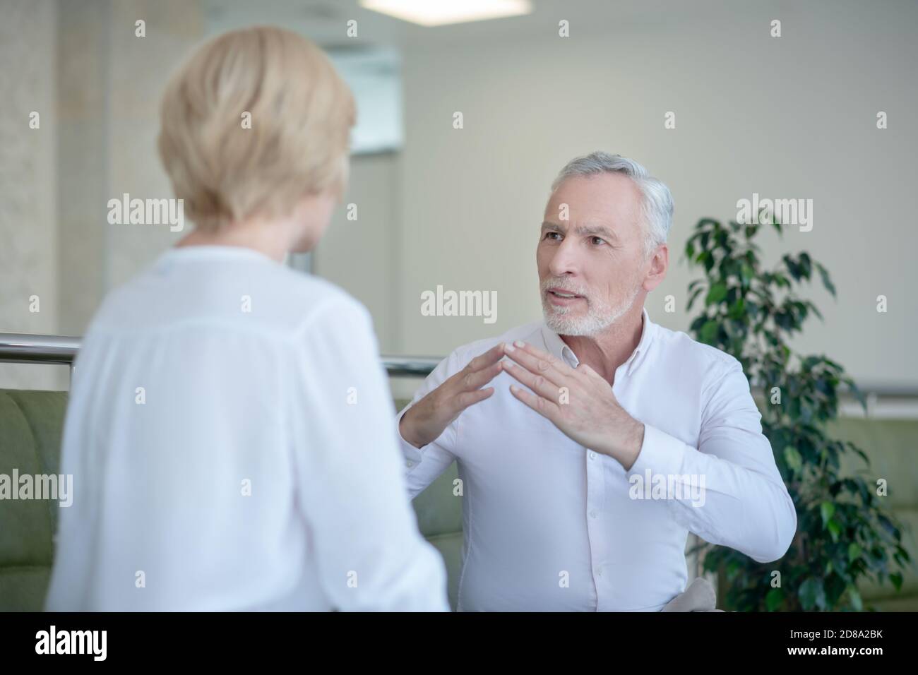 Bearded gray-haired man and blonde woman talking using sign language ...