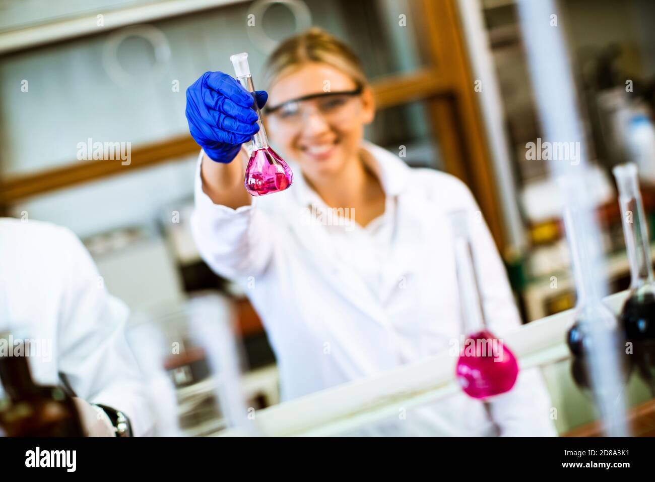 Pretty young female scientist examining liquid in biochemical lab Stock ...