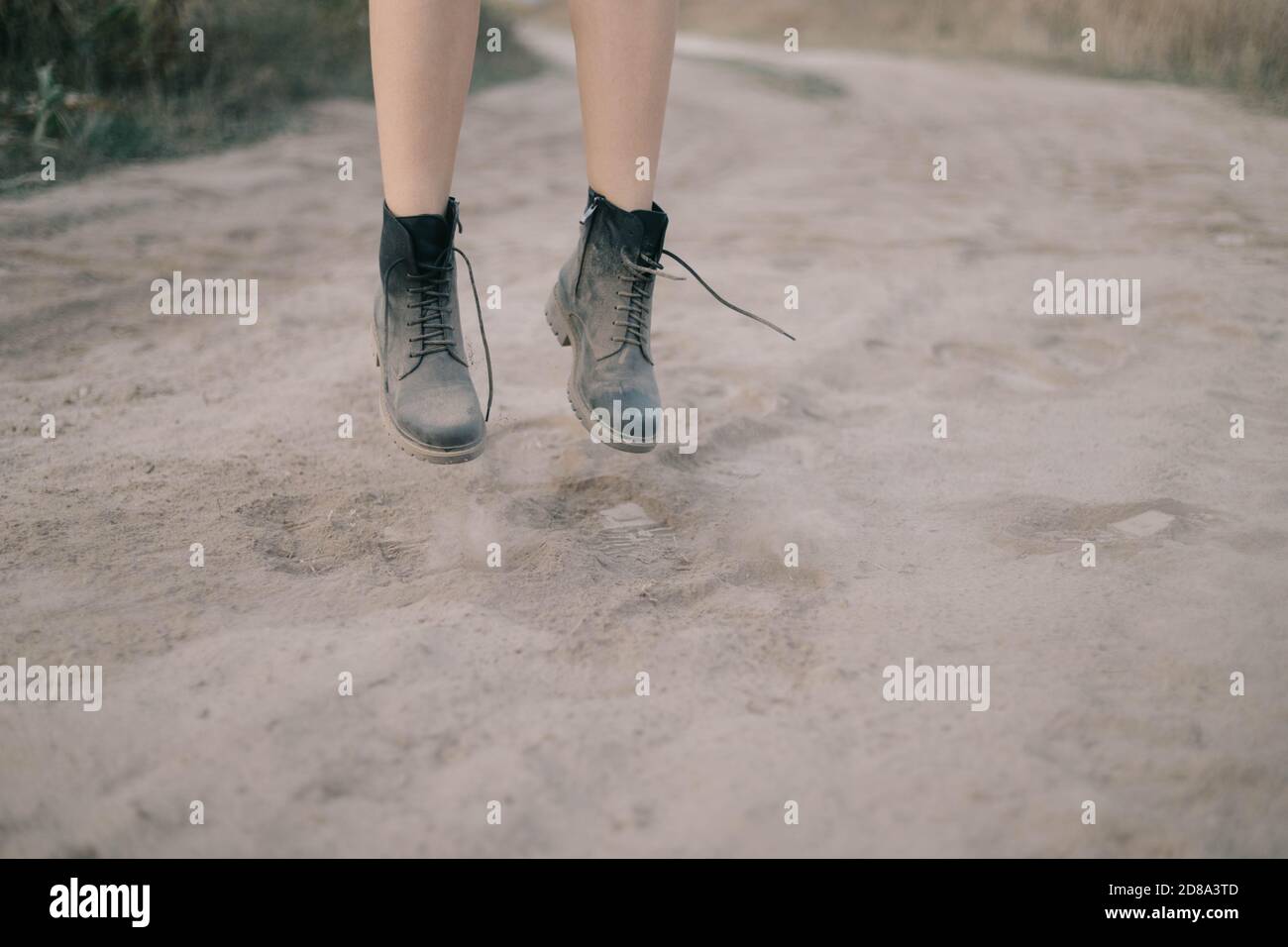 female legs jumping in the desert through fine dust carrying clouds of ...