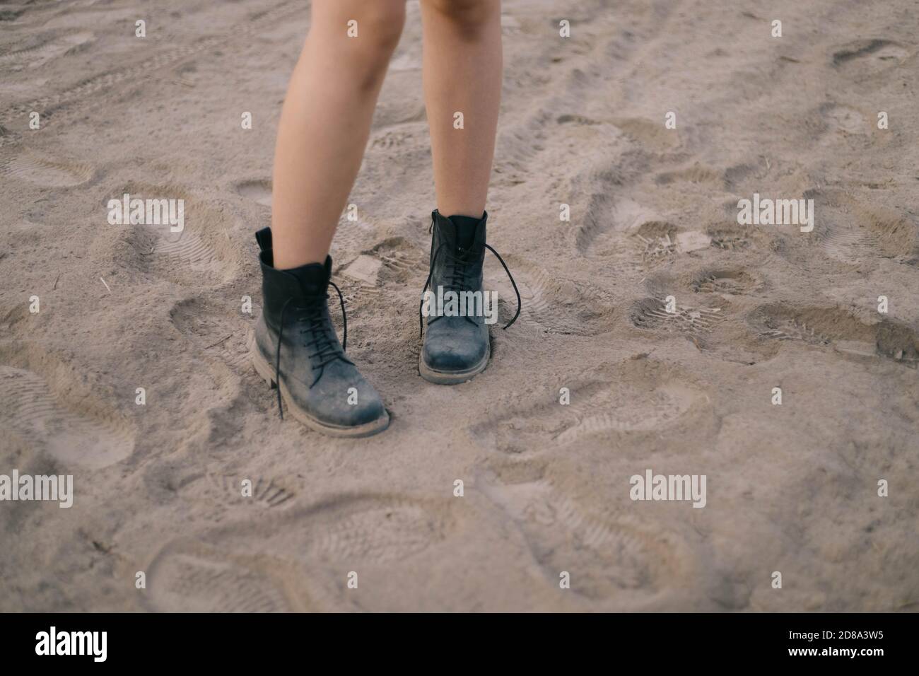 female legs jumping in the desert through fine dust carrying clouds of ...