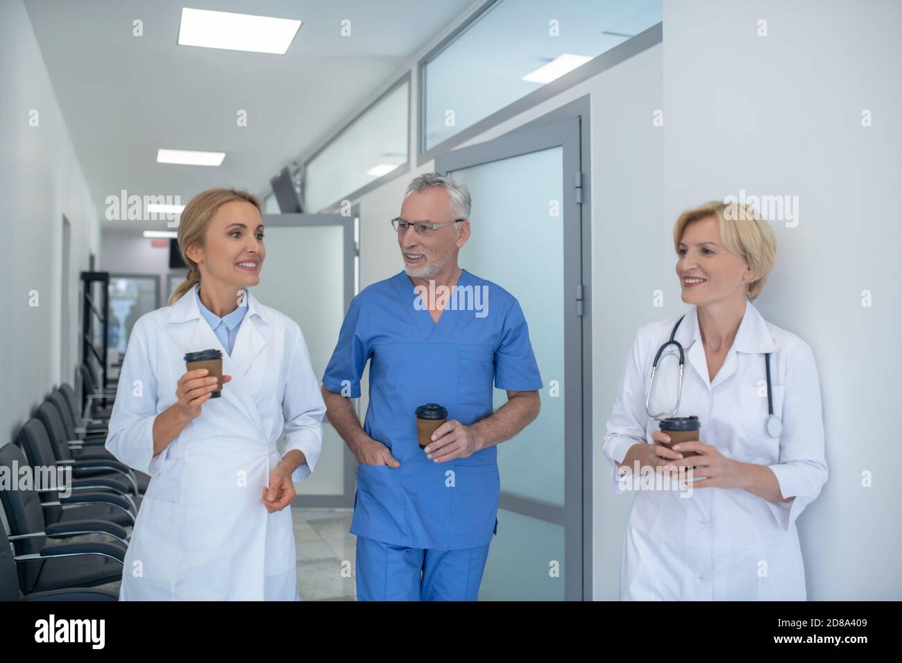 Group of smiling doctors enjoying coffee in the corridor Stock Photo ...