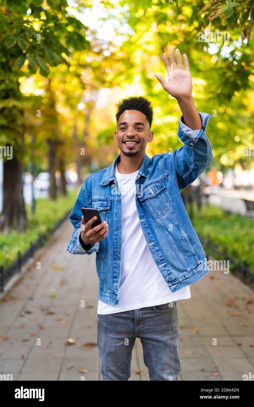 Happy black man waving hand on hello gesture looking at camera standing ...