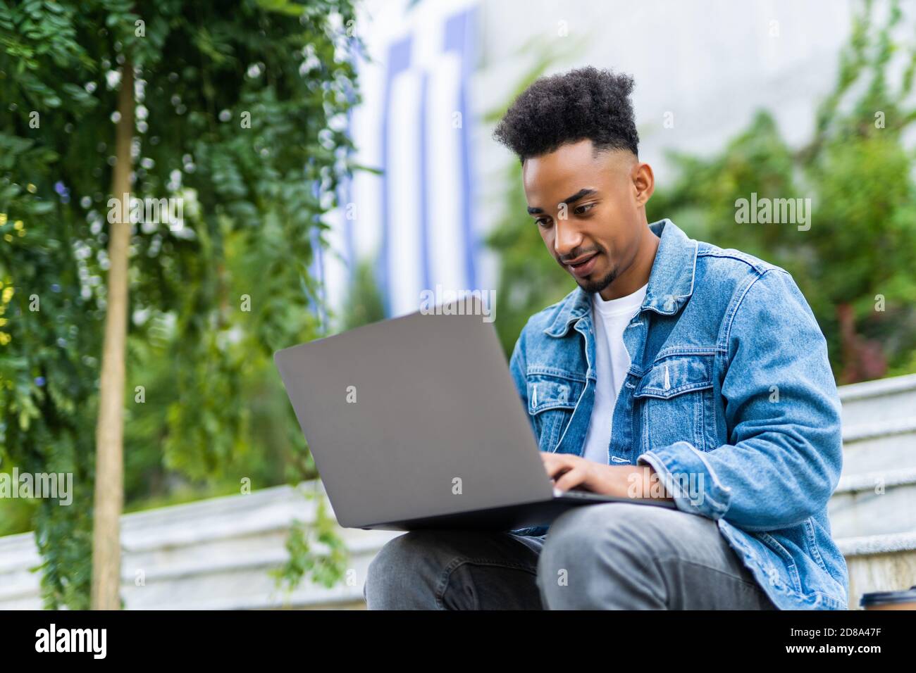 Pensive African Man working on Laptop, Sitting on Bench Stock Photo - Alamy