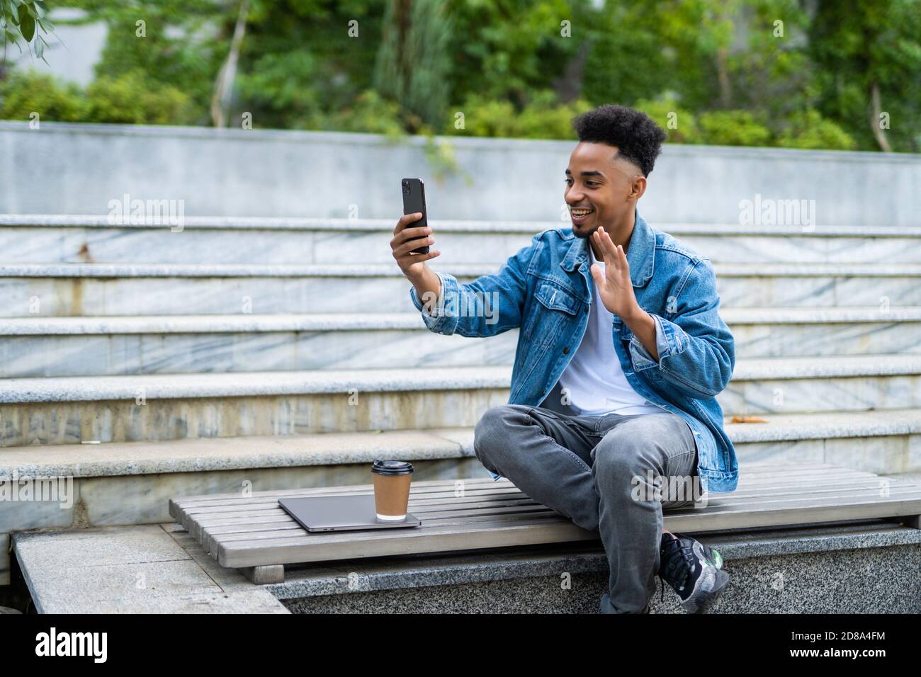 Smiling young african man in casual clothes making video call with ...