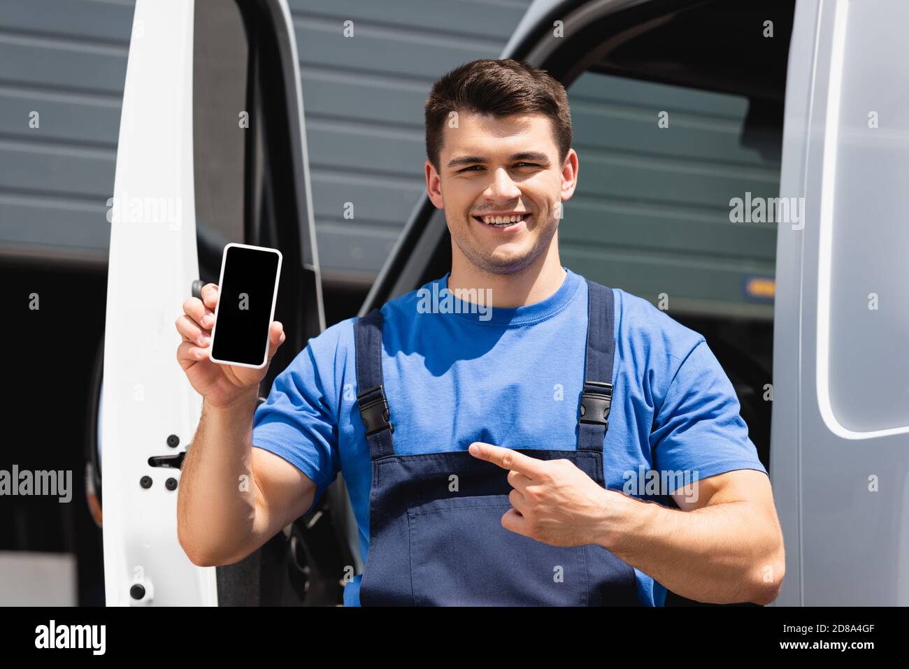 Loader pointing with finger at smartphone with blank screen near truck ...