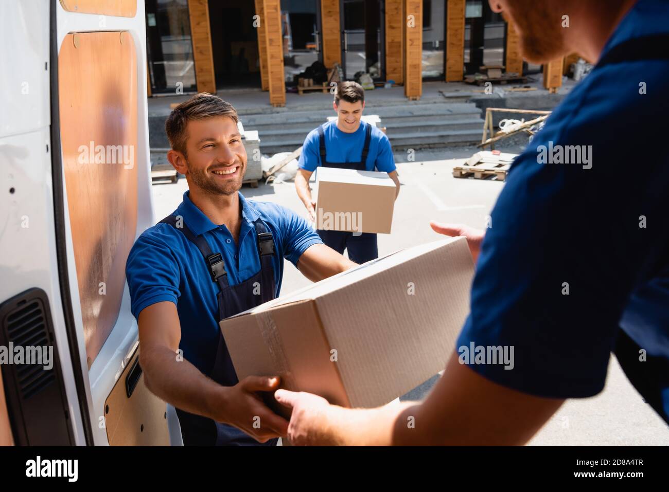 Selective focus of loader giving carton box to colleague in truck on ...