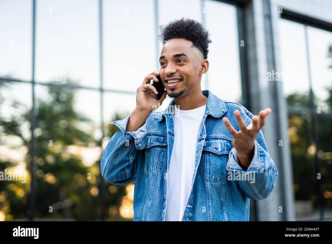 Young handsome Afro American man standing in front of huge modern ...
