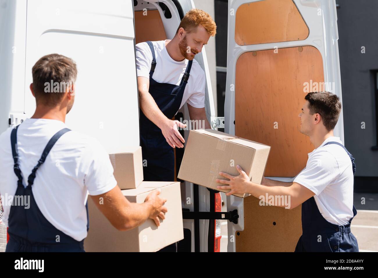 Selective focus of loader giving cardboard box to colleague while ...