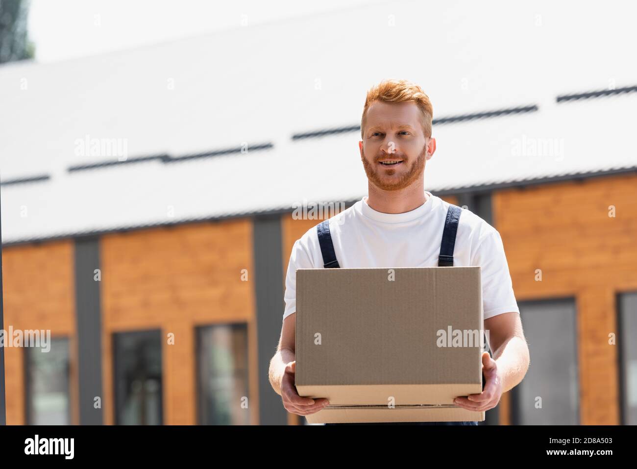 Loader holding cardboard box on urban street Stock Photo - Alamy