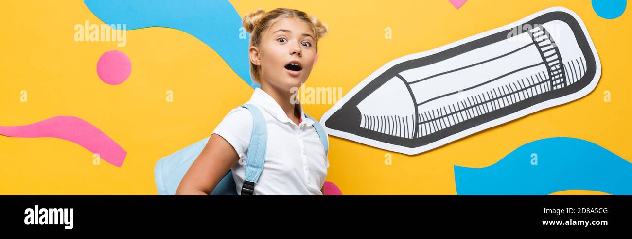 horizontal concept of amazed pupil looking at camera on yellow ...