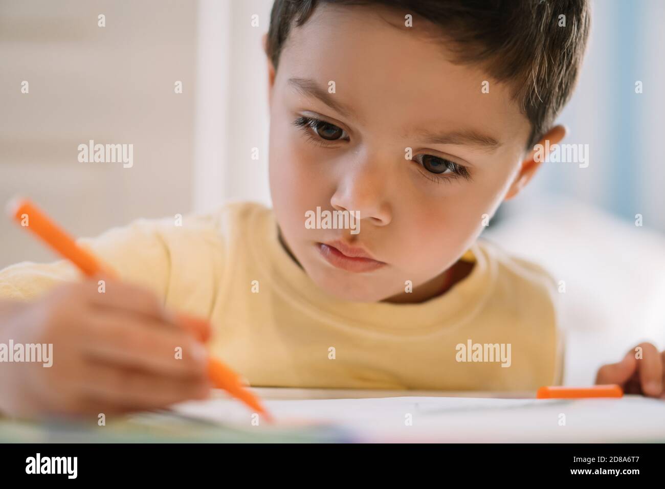 selective focus of adorable, concentrated boy drawing with felt pen ...