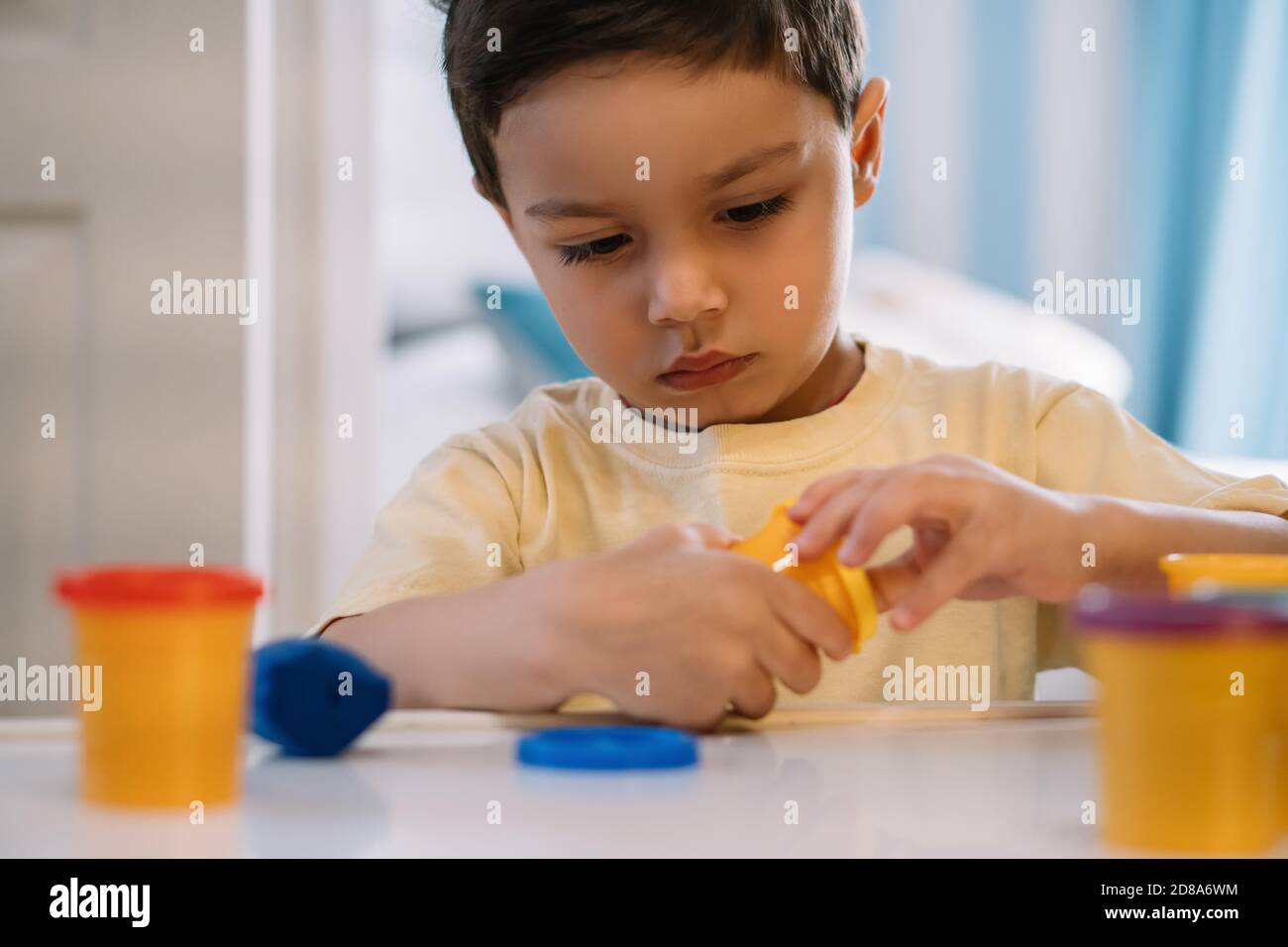 selective focus of attentive, adorable boy opening container with ...
