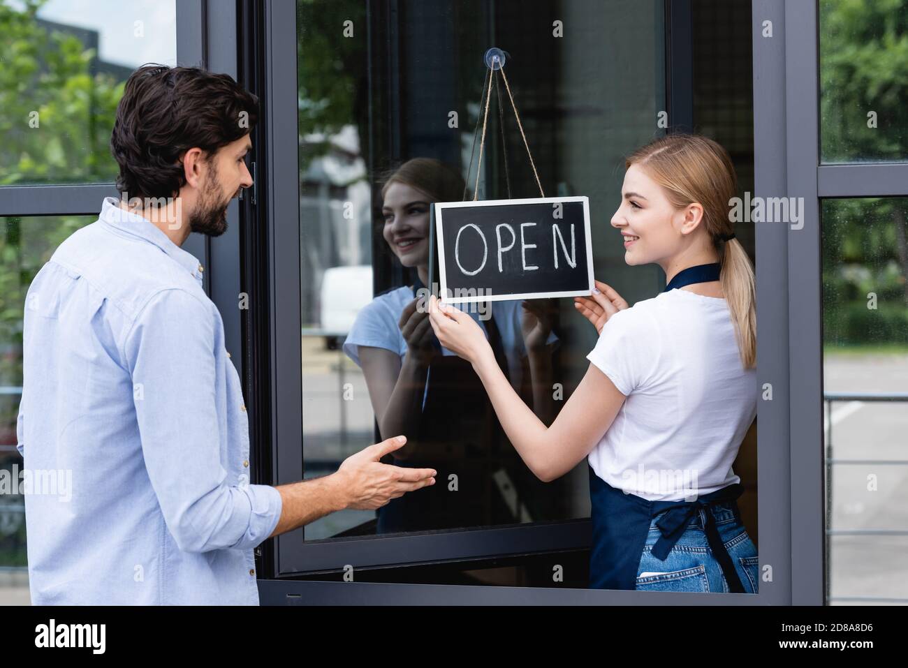 Customer pointing with hand near smiling waitress holding signboard ...