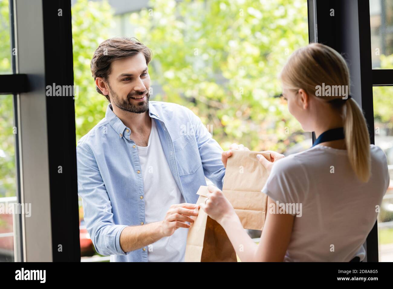 Selective focus of handsome man receiving packages from waitress at ...