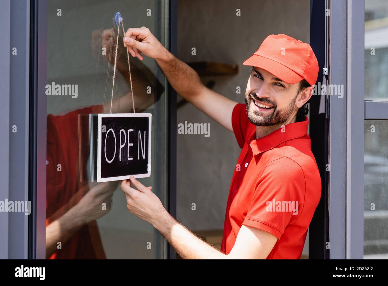 Side view of positive waiter in uniform hanging signboard with open ...