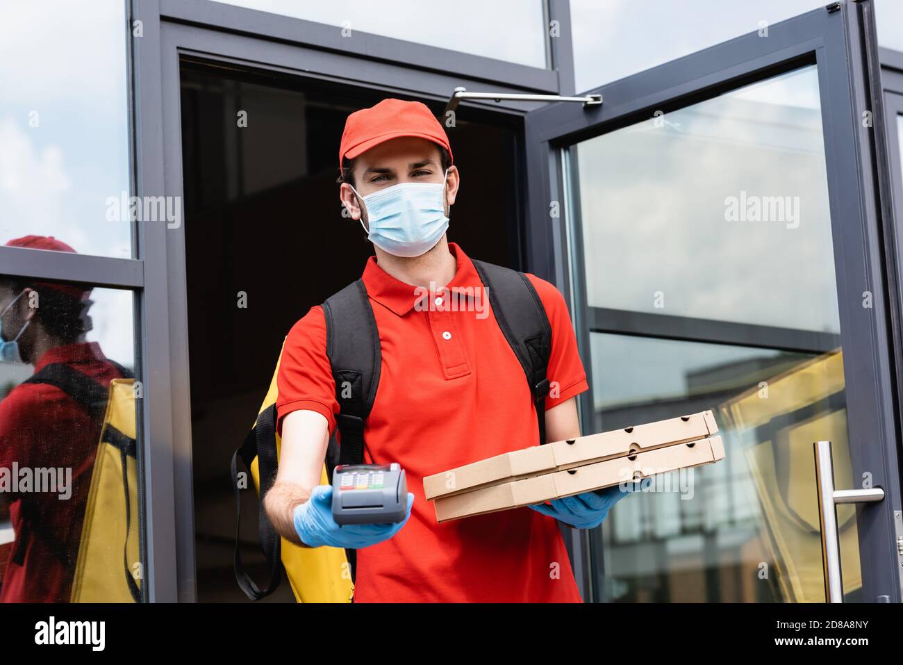 Selective focus of courier holding pizza boxes and payment terminal on ...