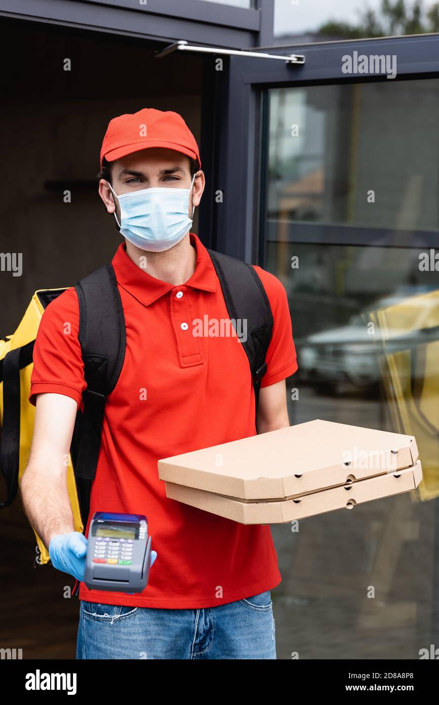 Courier in medical mask and latex glove holding payment terminal and ...