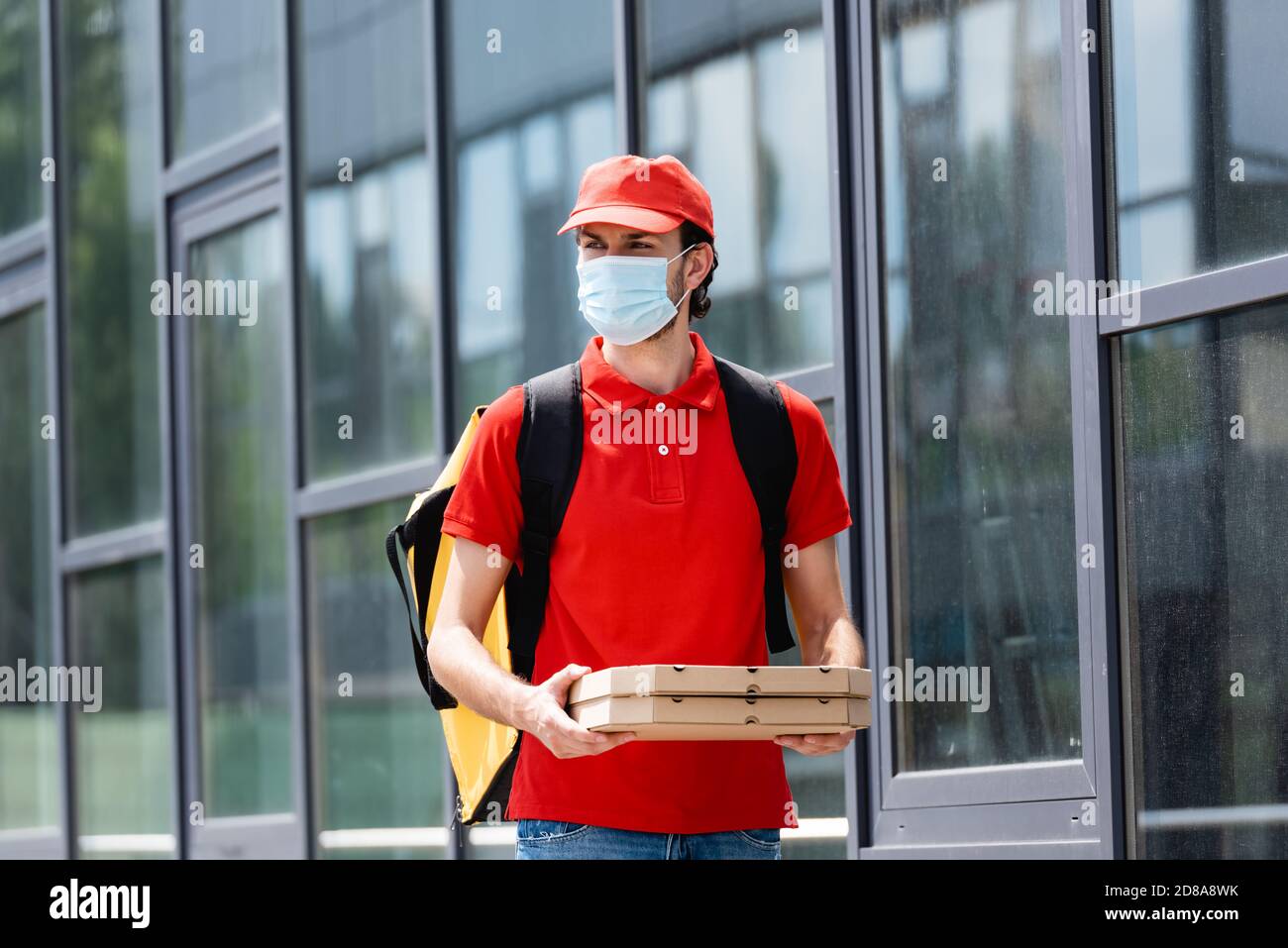 Delivery man in medical mask holding pizza boxes on urban street Stock ...