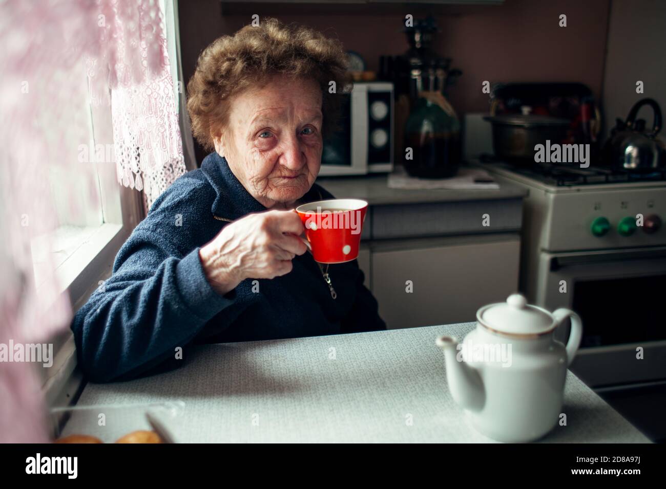 An old woman drinking tea in the kitchen at her home Stock Photo - Alamy