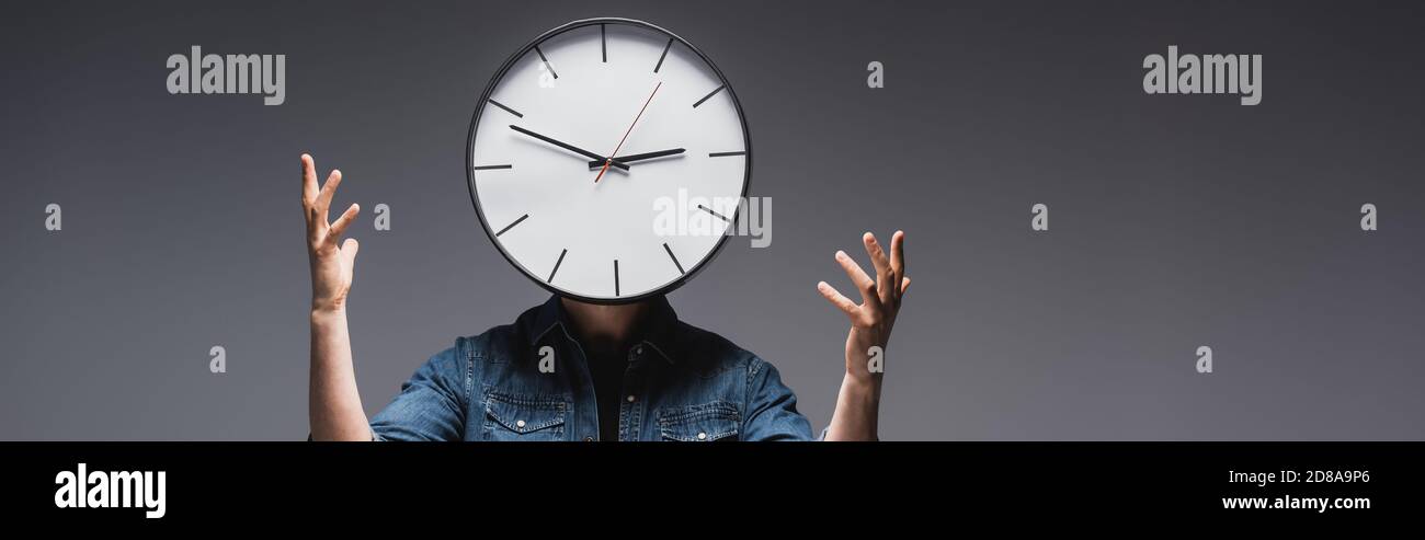 Horizontal image of man with clock on head gesturing on grey background ...