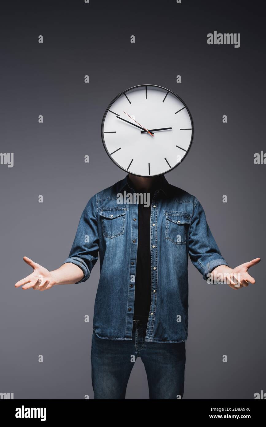 Man with clock on head pointing with hands on grey background, concept ...