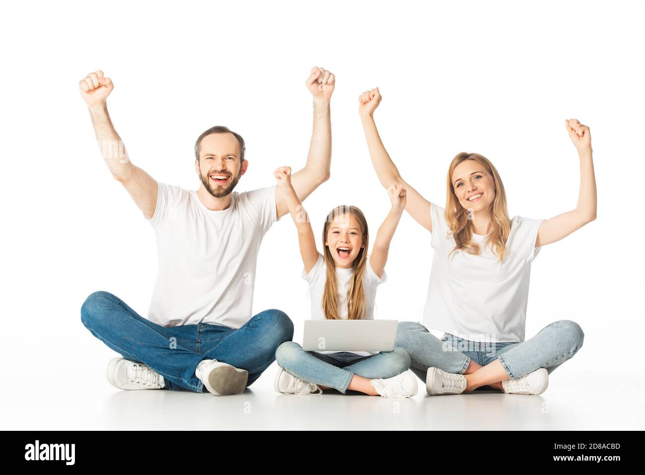 excited parents sitting on floor near happy daughter with laptop ...