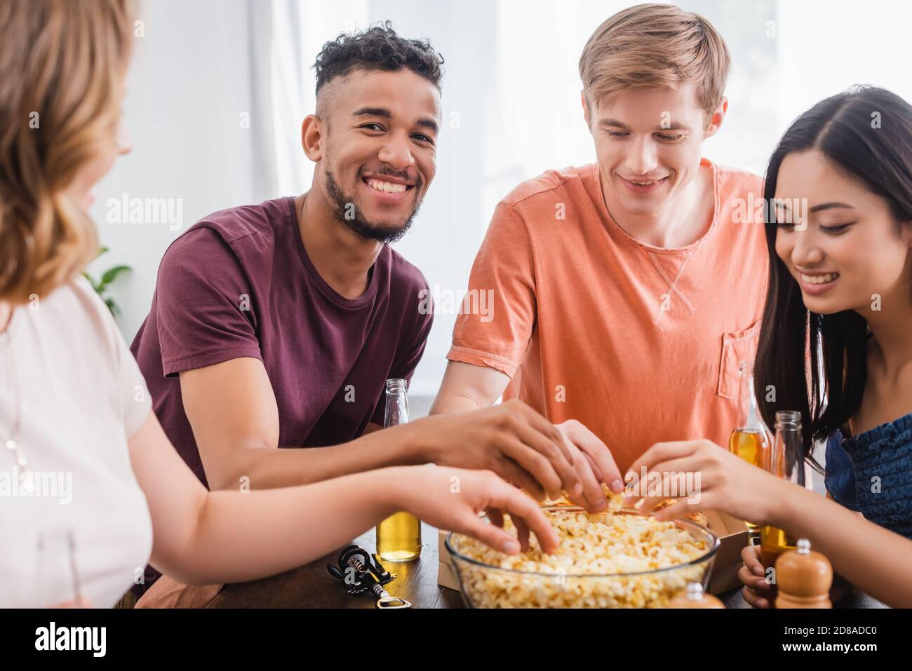 selective focus of excited multicultural friends taking popcorn from ...
