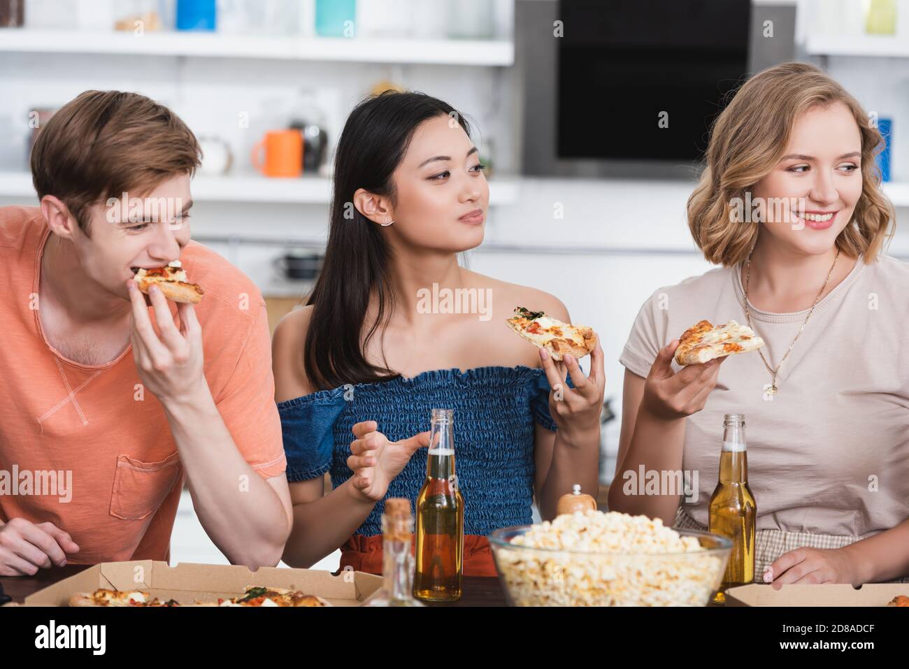 joyful multicultural friends eating pizza near bowl of popcorn Stock ...