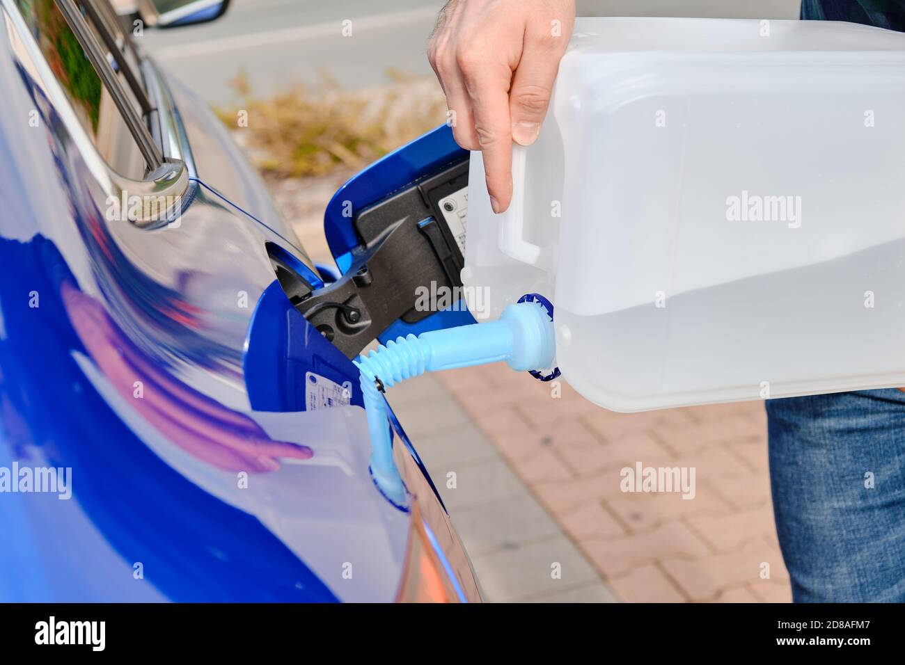 Close up man filling a diesel engine fluid from canister into the tank ...