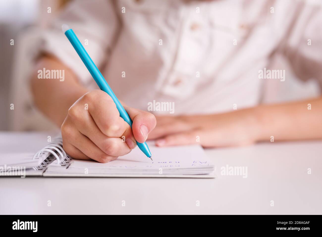 Close up of child's hand making notes in the writing pad lying on the ...