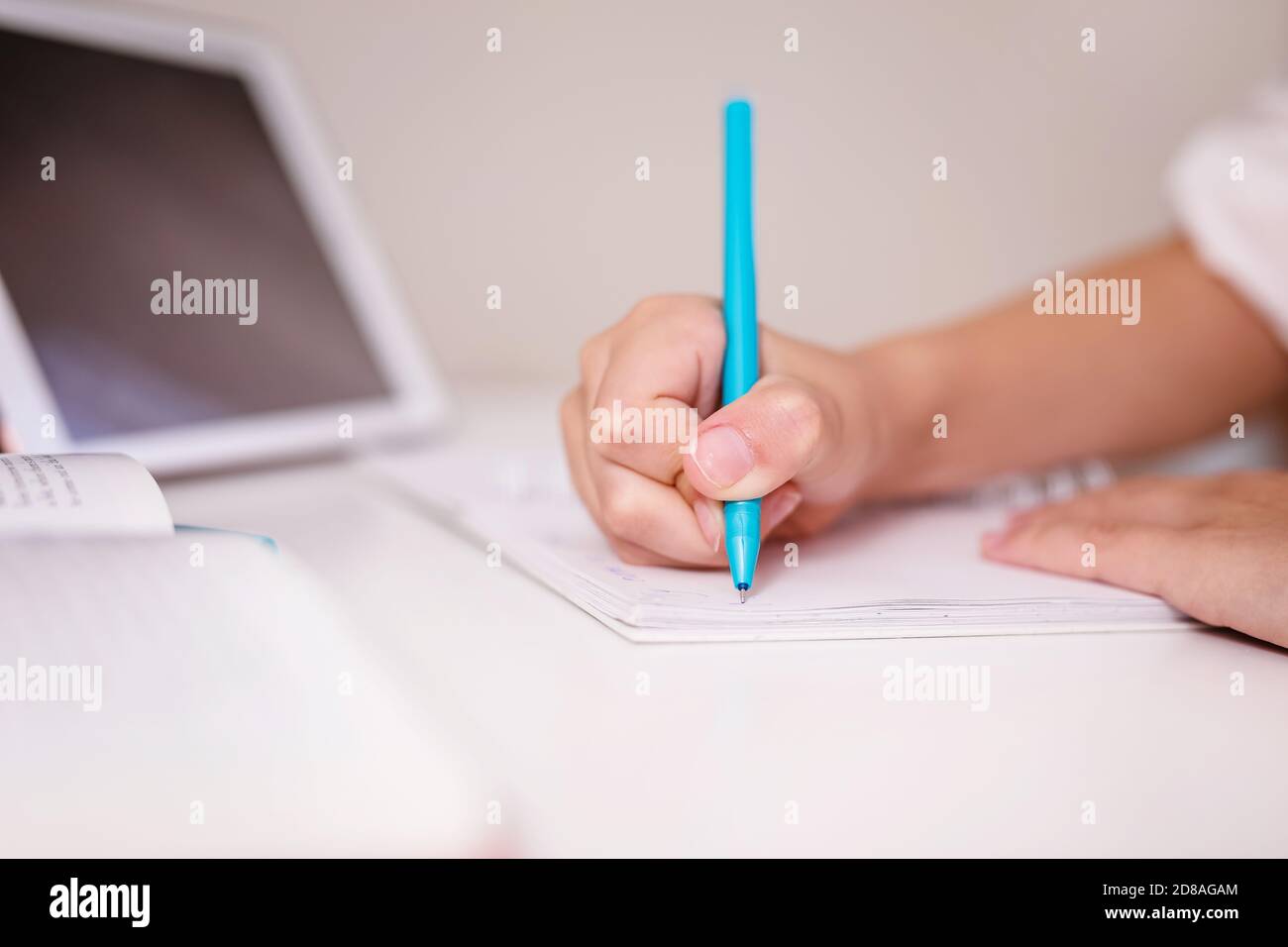 Close up of child's hand making notes in the writing pad lying on the ...