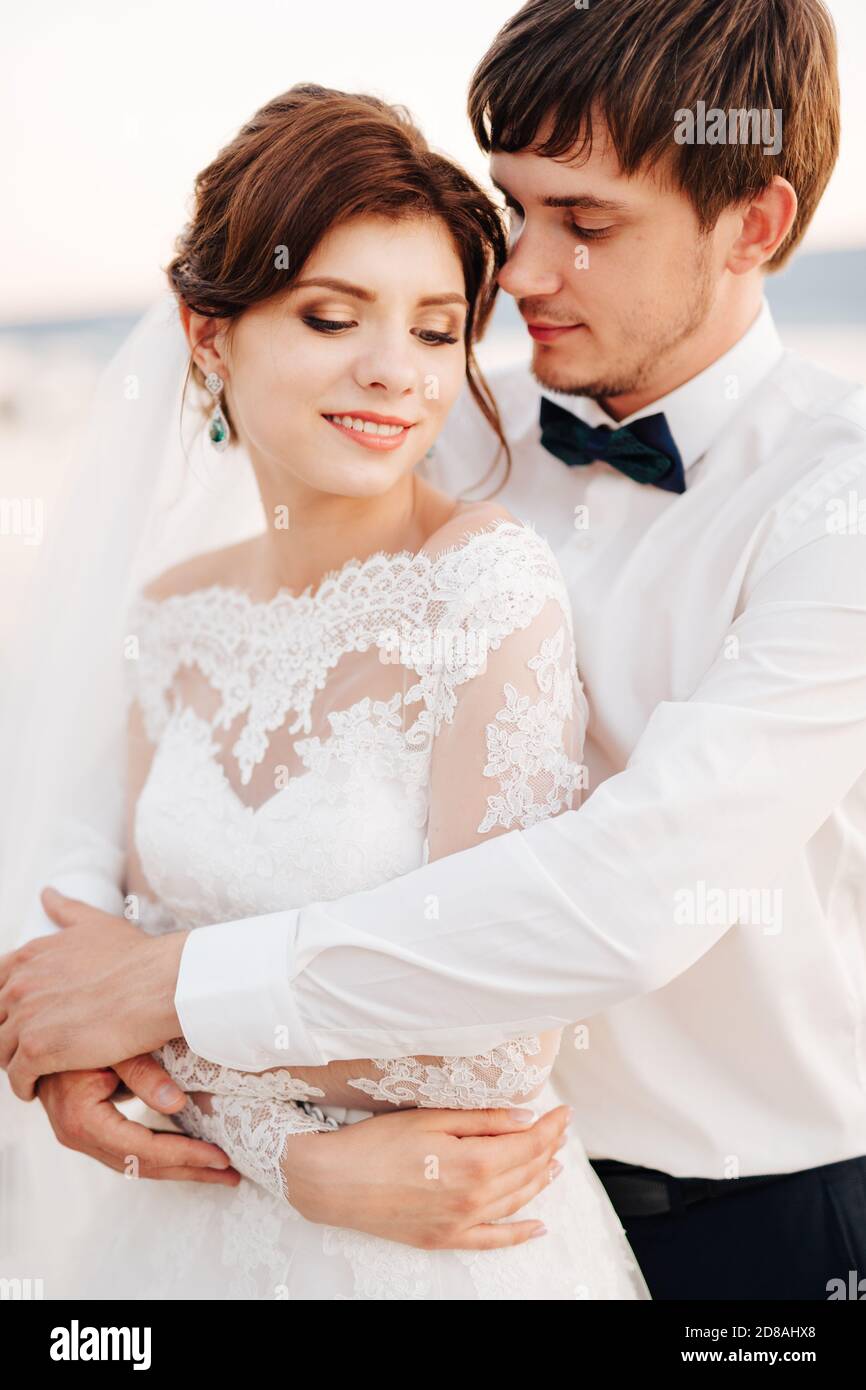 the groom gently hugs the bride from behind Stock Photo - Alamy