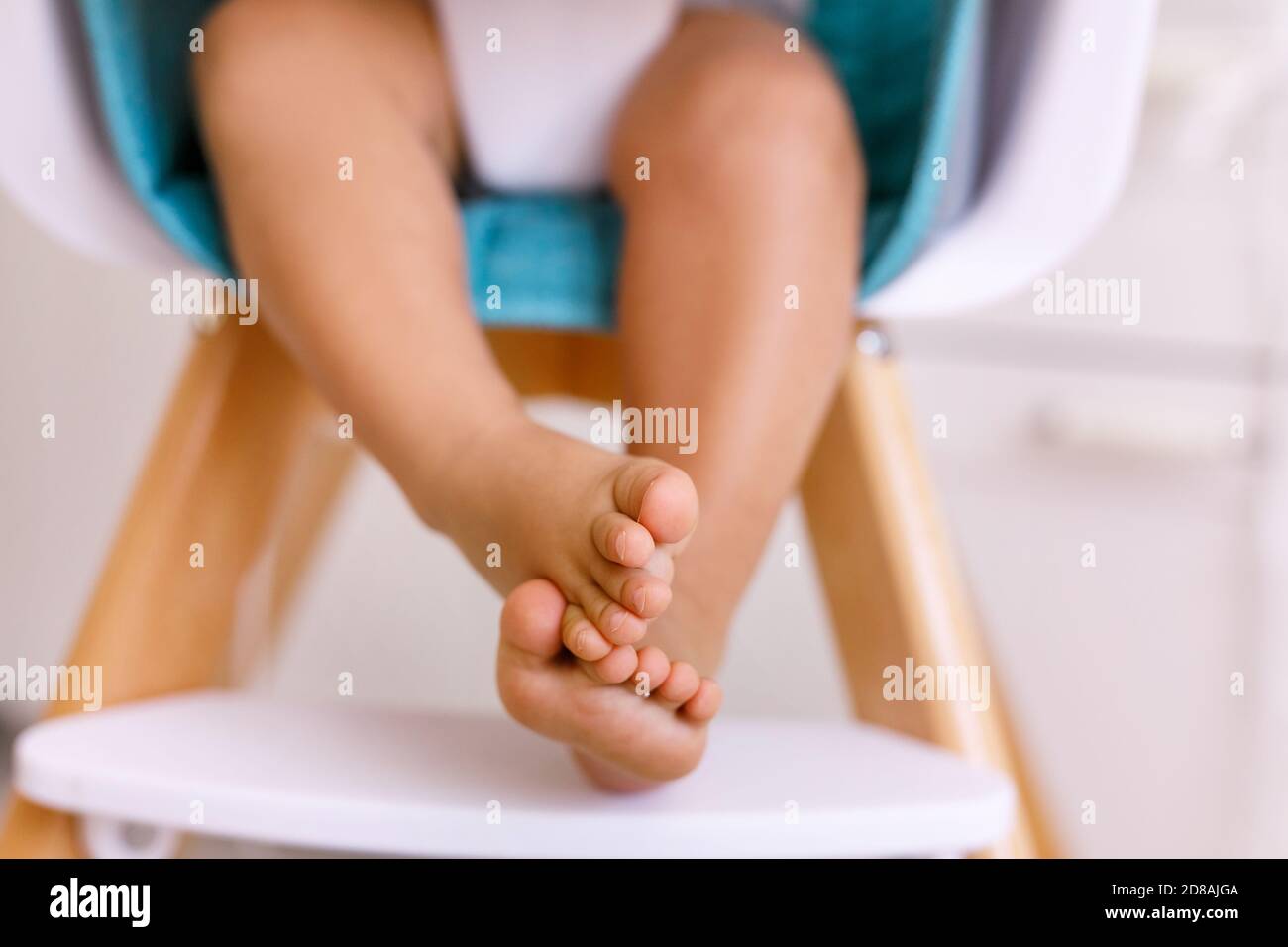 One years old child's feet on high chair while he is eating at kitchen ...
