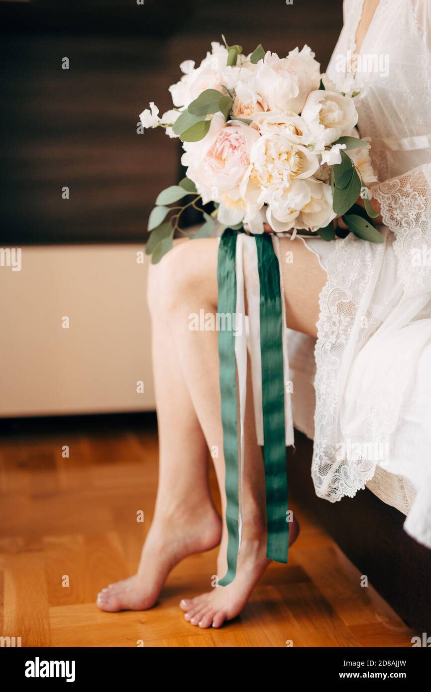 bridal bouquet of cream roses and eucalyptus lying on the bride's legs ...