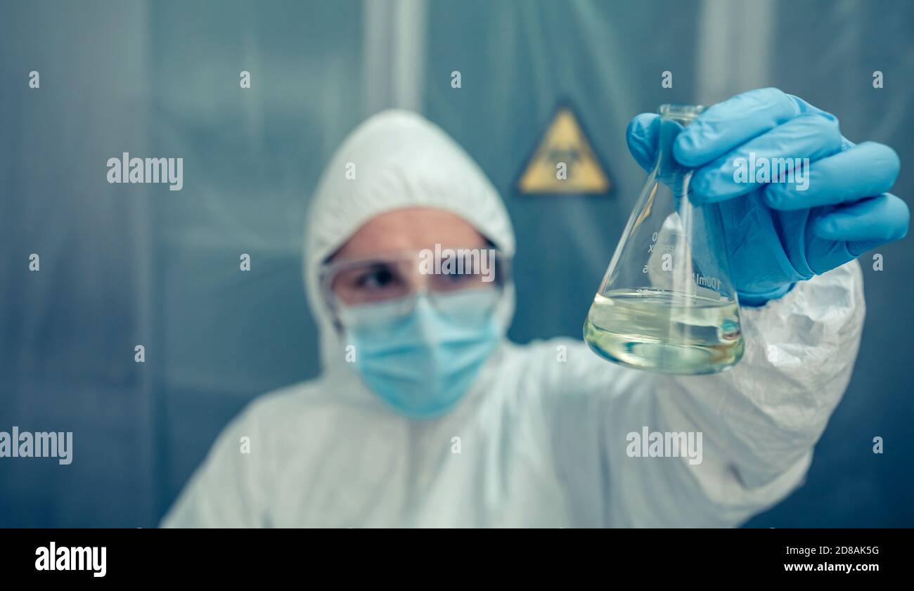 Scientist with protection suit looking test tube in the laboratory ...