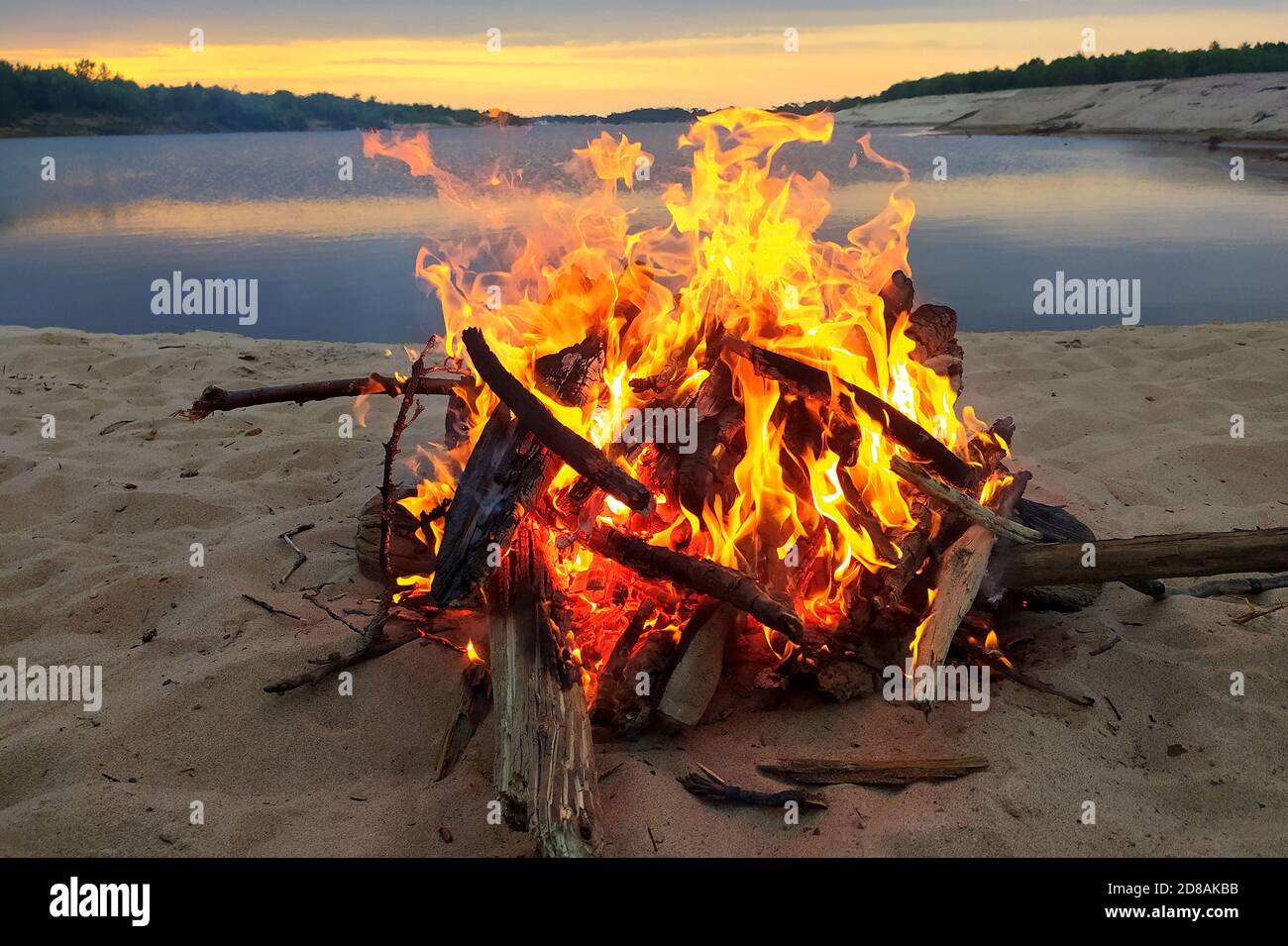 A bonfire on the river bank. Fire on the beach. The wood is burning on ...