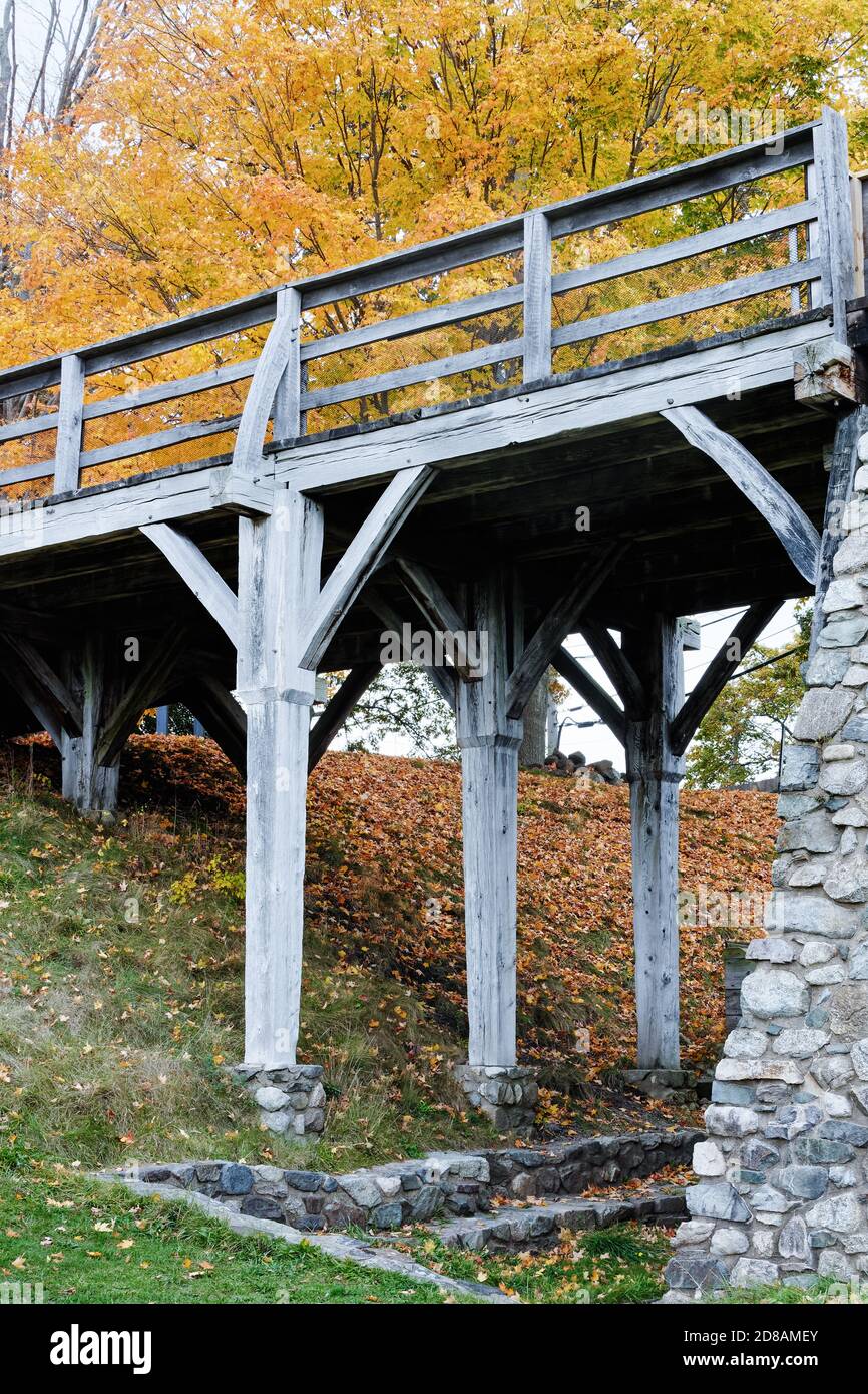 A gray wood bridge surrounded by brightly colored fall foliage leads to ...
