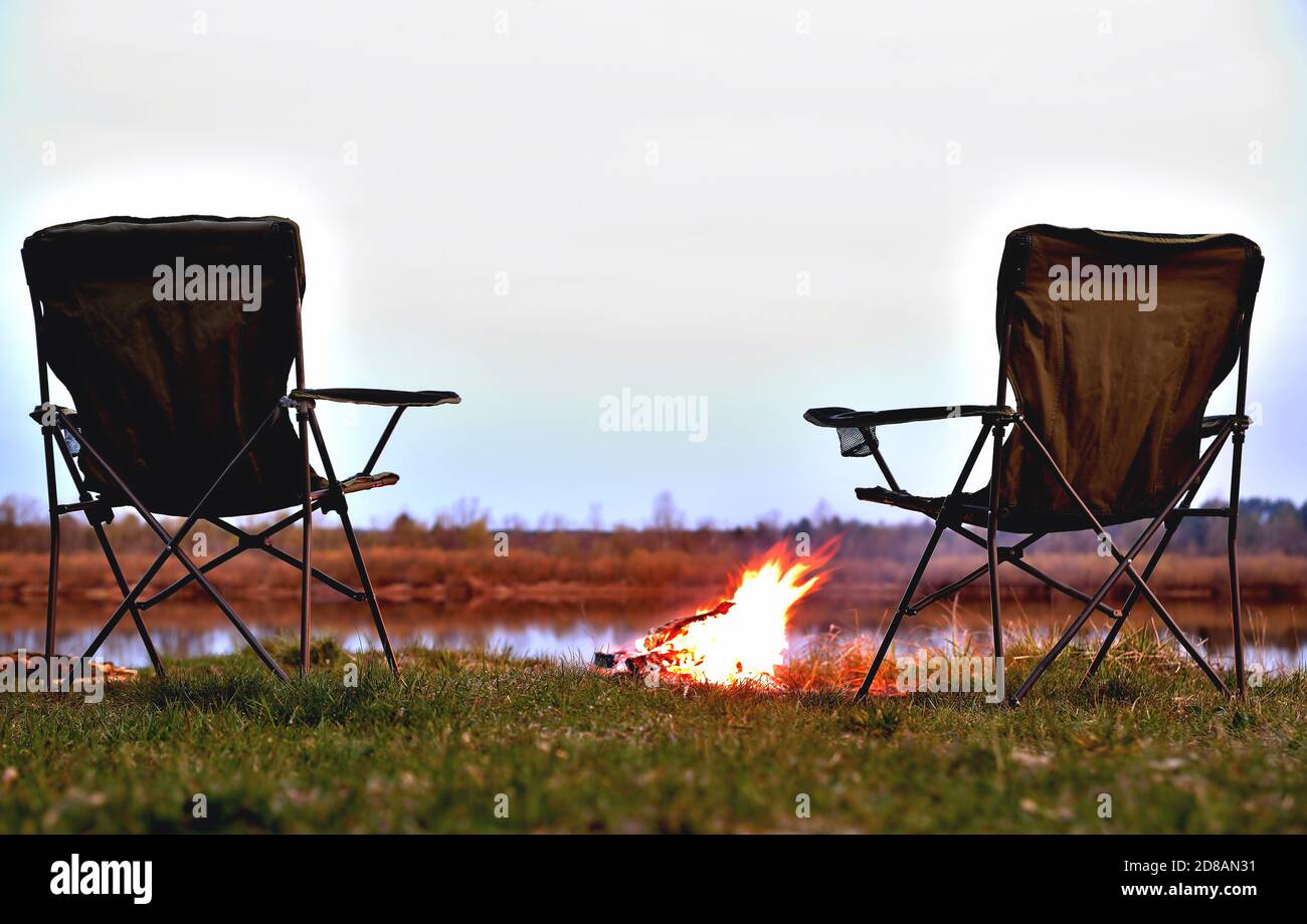 A pair of tourist chairs, a folding chair, a bonfire on the river bank ...