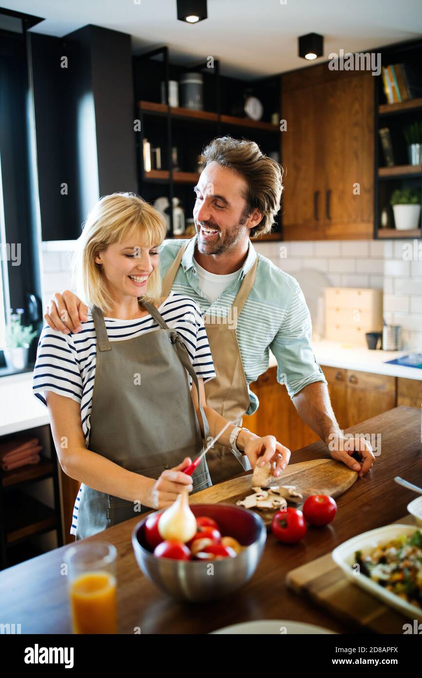 Happy couple cooking healthy food and having fun together in their ...