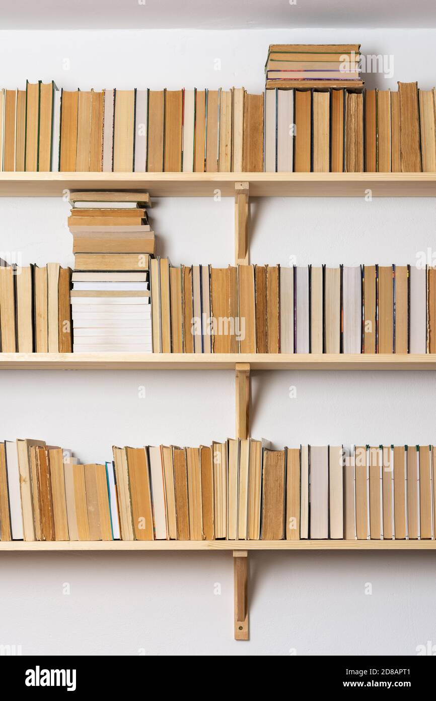 Light wooden bookshelves with hardback overturned books in white ...
