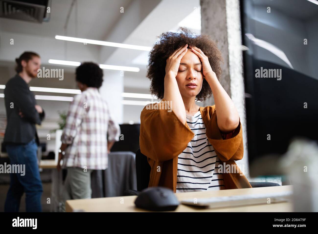 Overworked and frustrated young woman in front of computer in office ...