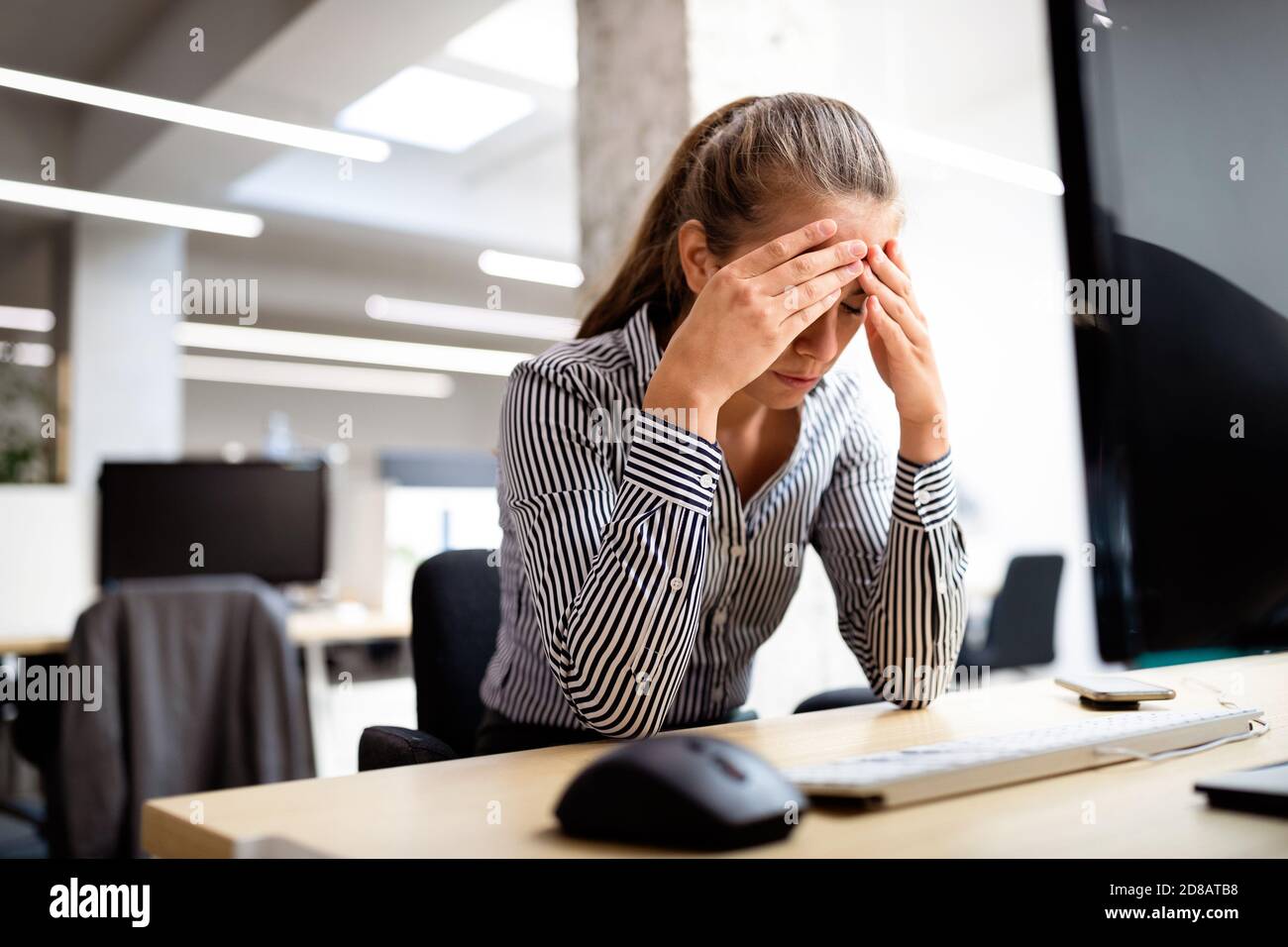 Overworked and frustrated young woman in front of computer in office ...