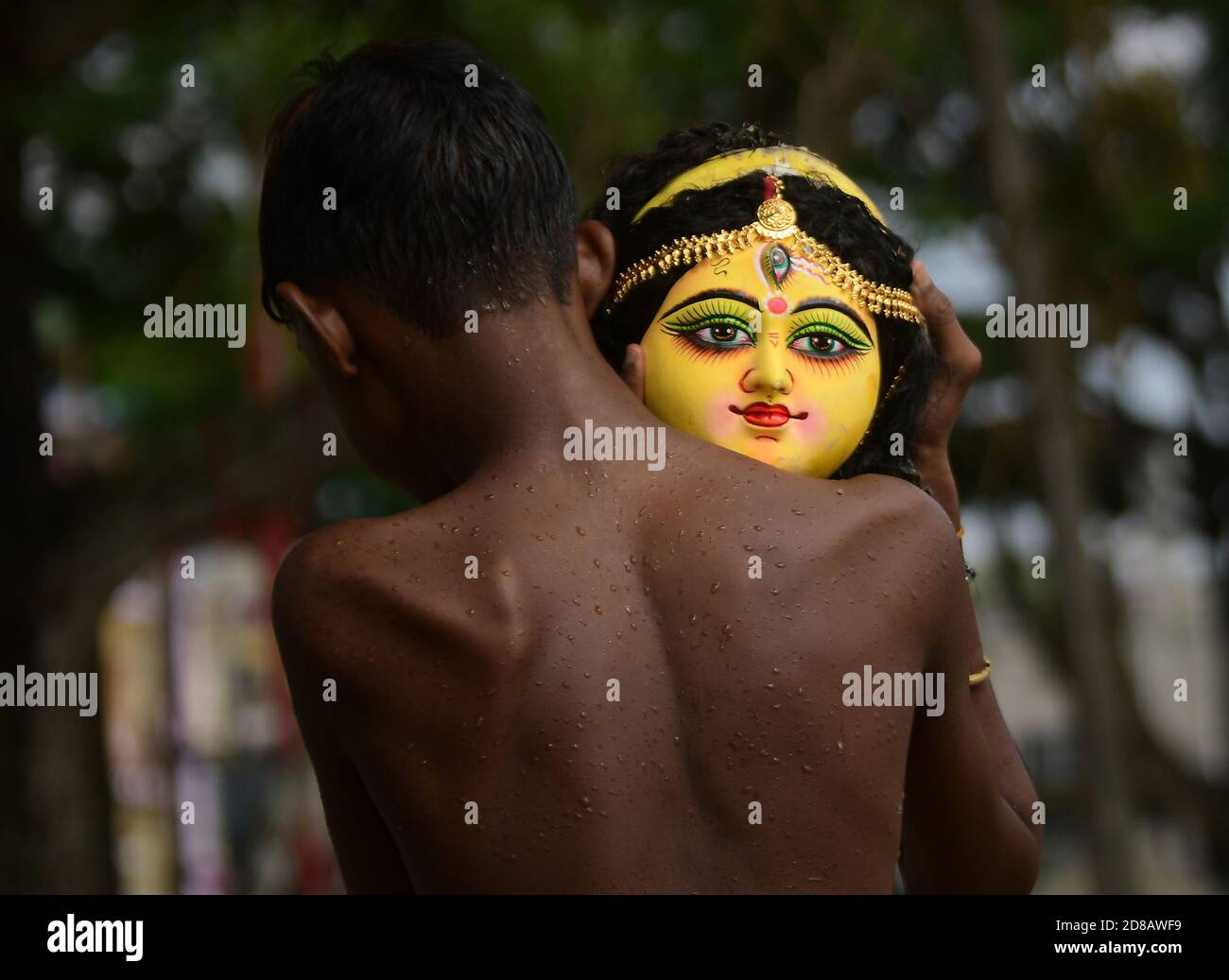 A child holds the head of an idol of the goddess Durga during an ...