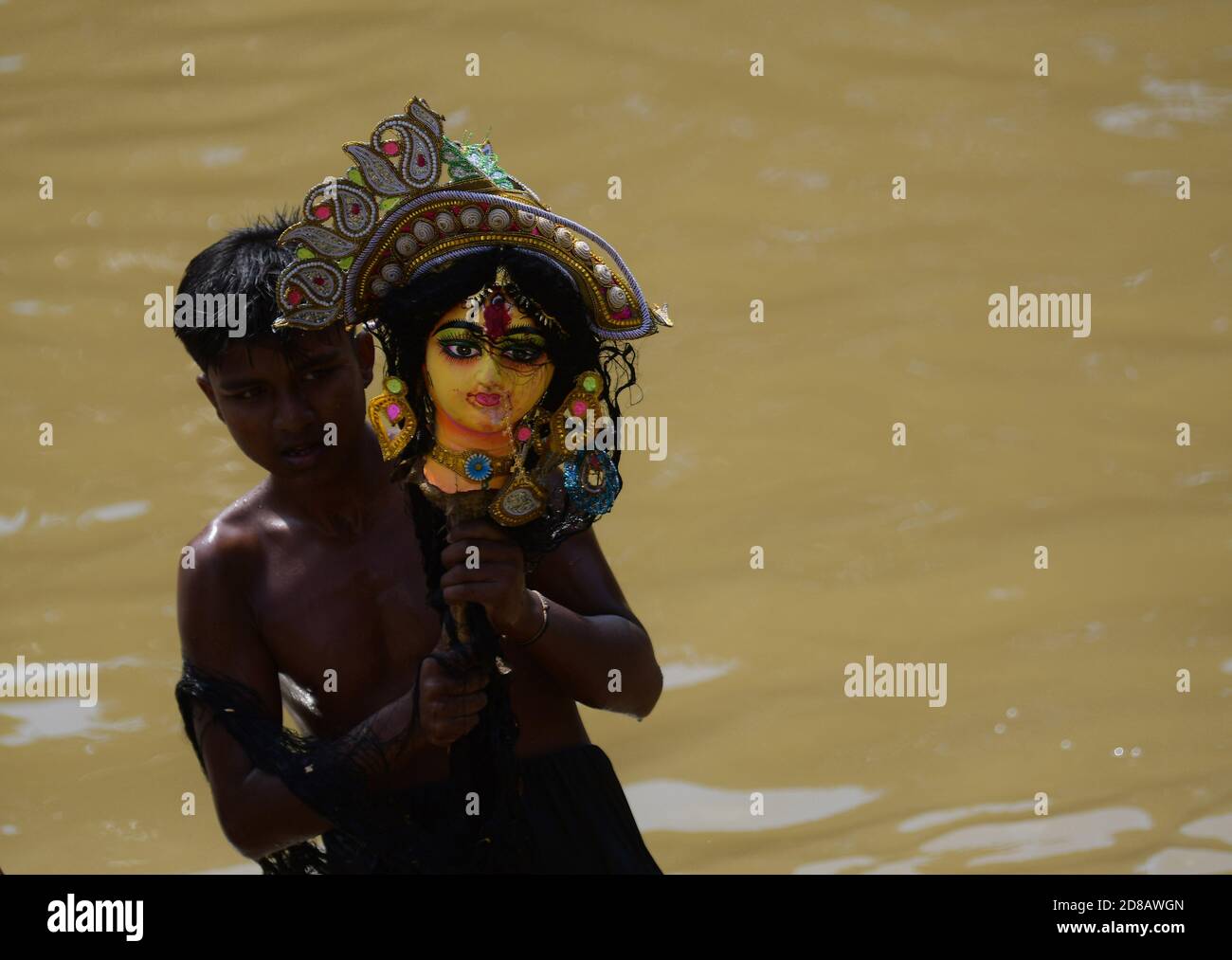 A child holds the head of an idol of the goddess Durga during an ...