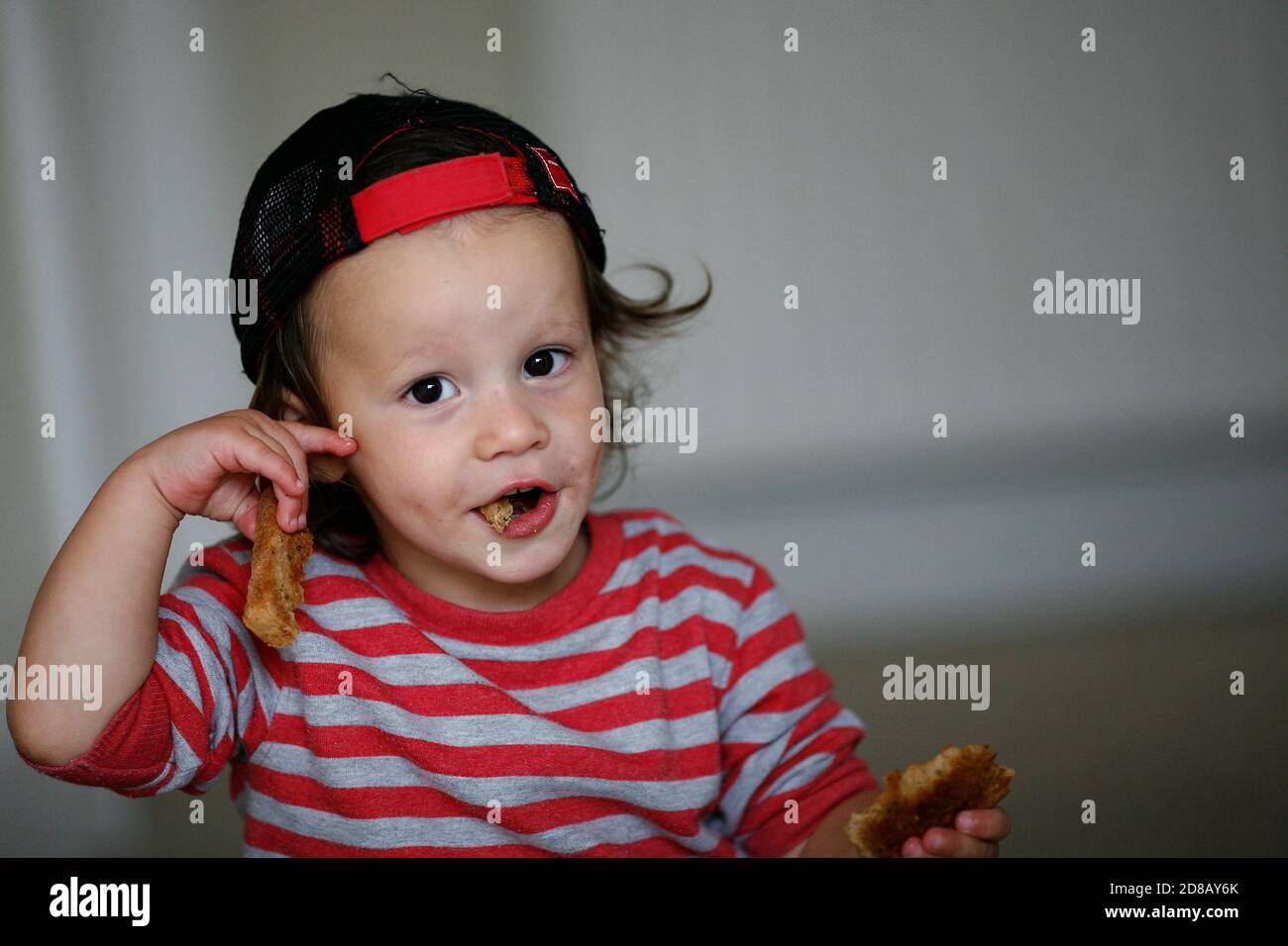 A little boy eating toast in a cap and striped top . ©PRWPhotography ...